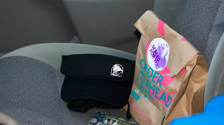 Жүргүнчү тараптагы отургучта Taco Bell кара калкалоочу, сумка жана Уэйн Стейт Университетинин ID идентификатору.