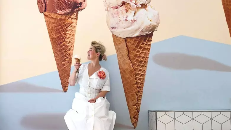 Jeni Britton Bauer sentada cun cono cheo de xeado diante dunha gran imaxe de conos de xeado