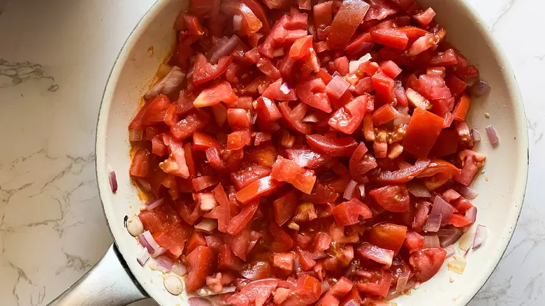 Saltitaj tomatoj, cepoj kaj ajlo en pato