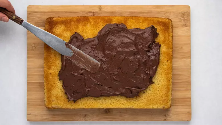 Përhapja e kremës me çokollatë mbi tortën e verdhë