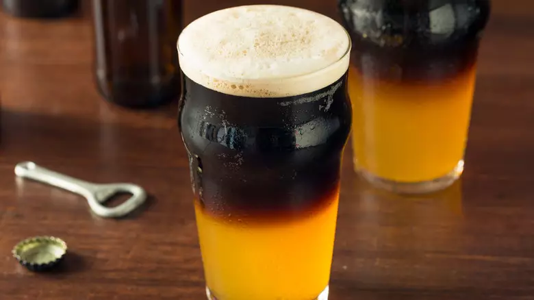 Sort og solbrun øl i glas på træbord