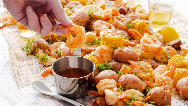 Instant Pot Shrimp Boil ကိုပိတ်ပြီး အရသာရှိသော ထောပတ်ဖြင့် ပုဇွန်ကို လက်ဖြင့်နှစ်ပါ။