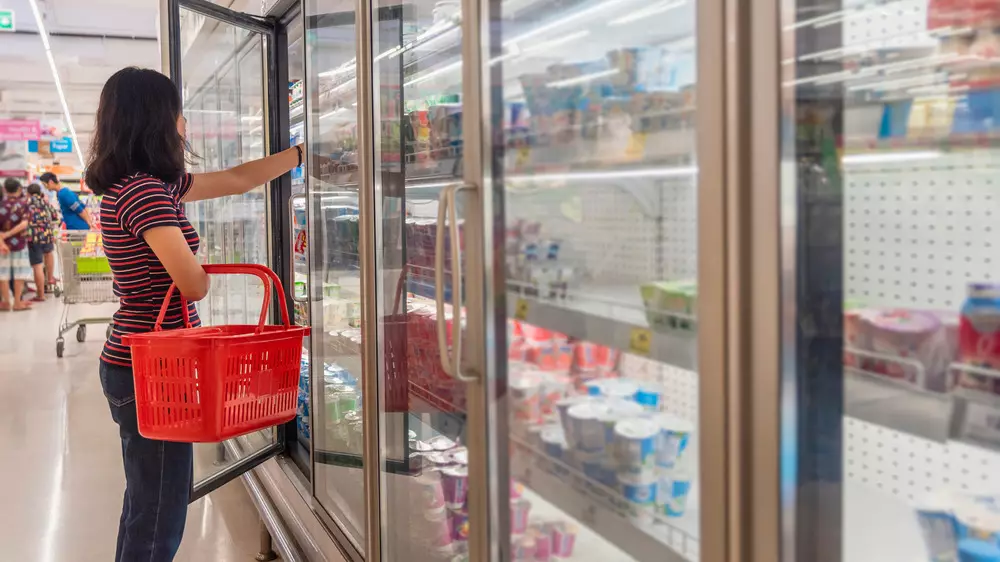 Persoun Shopping an der gefruer Liewensmëttel Gang