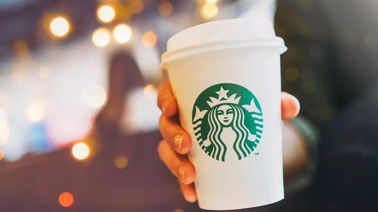 Person som håller en vit och grön Starbucks-kopp