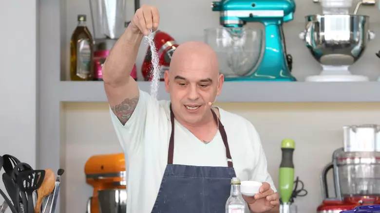 Michael Symon drysser salt i et blåt forklæde