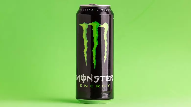 Monster enerģijas dzēriena skārdene uz zaļa fona