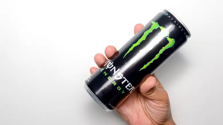 Osoba koja drži tanku limenku Monster Energy Drinka