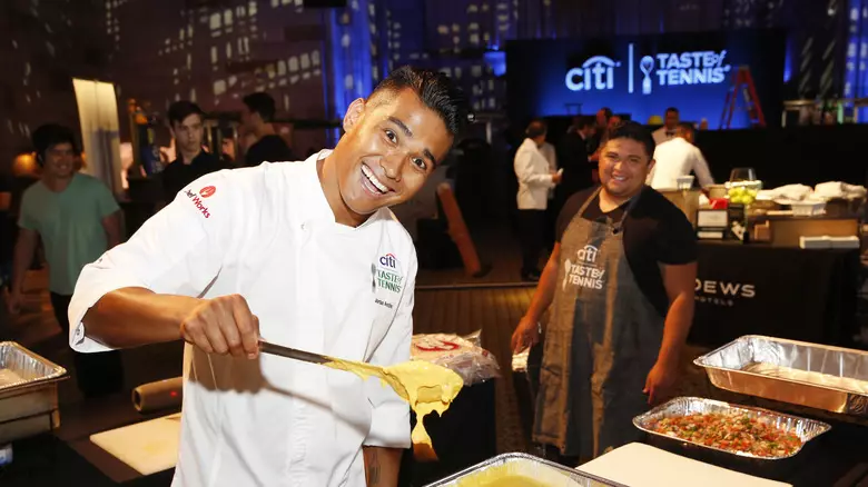 Jordan Andino lacht terwijl hij eten serveert