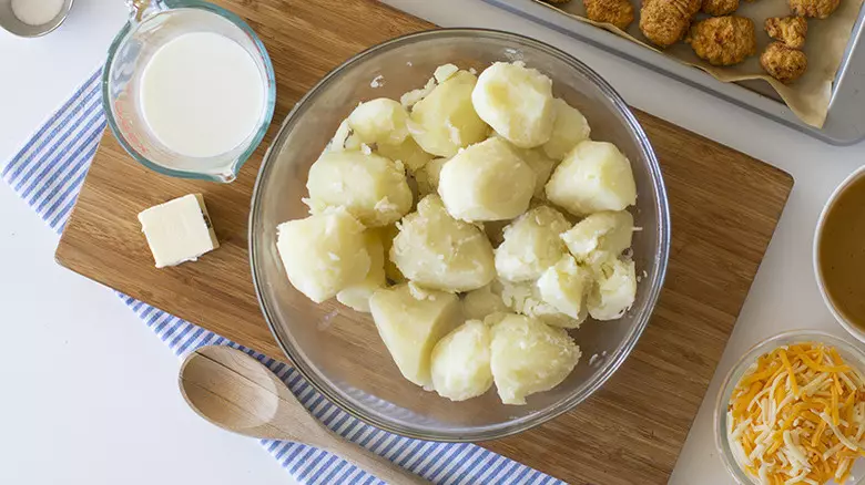 Patatas cocidas en un bol junto a la leche y la mantequilla