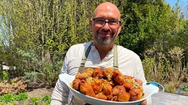 Michael Symon segurando um prato de comida