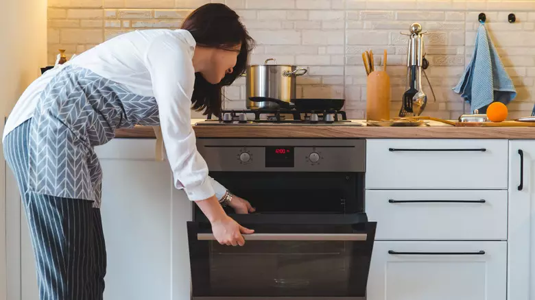 Mujer abriendo la puerta de un horno