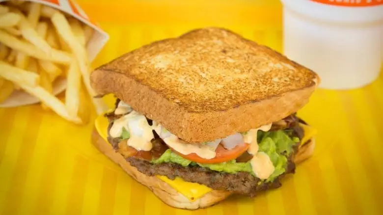 Whataburger Avokado Bacon Burger, patate të skuqura dhe pije në tryezë