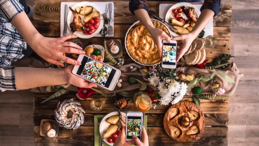 Menschen fotografieren einen Tisch mit Essen