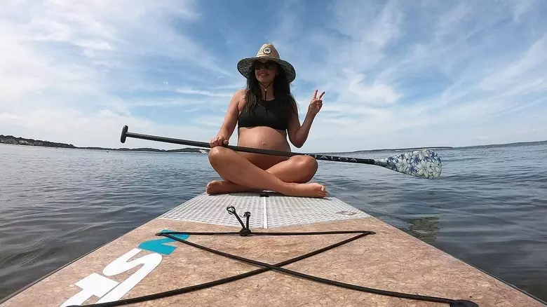 Katie Lee na dasci za veslanje daje znak mira