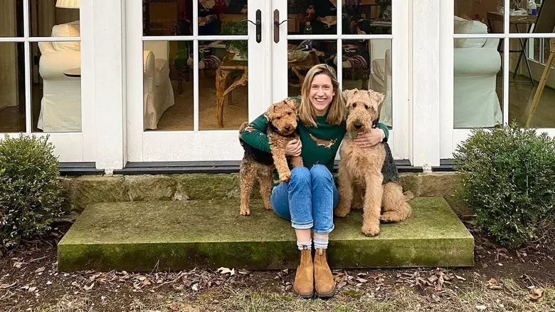 Лиди Хеук седи на затревена навес между две кучета