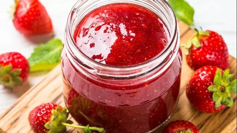 Sitiroberi Jam ni gilasi kan idẹ ti yika nipasẹ alabapade strawberries