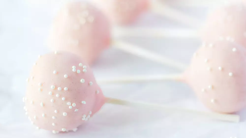 Imitación recubierta de caramelo rosa Starbucks cake pops con nonpareils de plata en un mostrador blanco