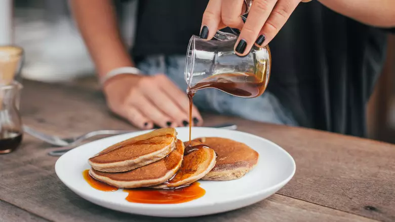 Pouring maple phoov rau pancakes