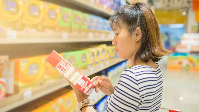 Wanita membaca label makanan di lorong runcit