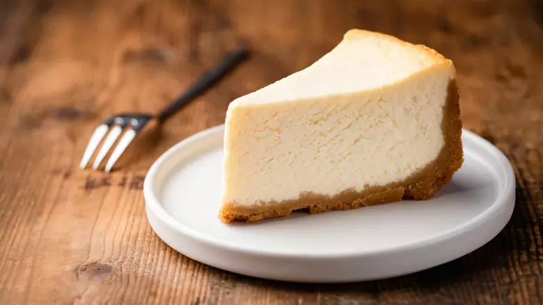 Skiva av cheesecake på en brun bakgrund