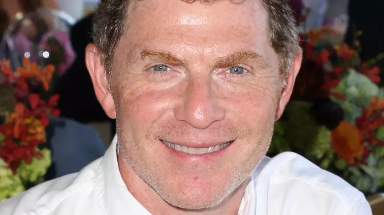 Bobby Flay s bílým knoflíkem sedí a usmívá se