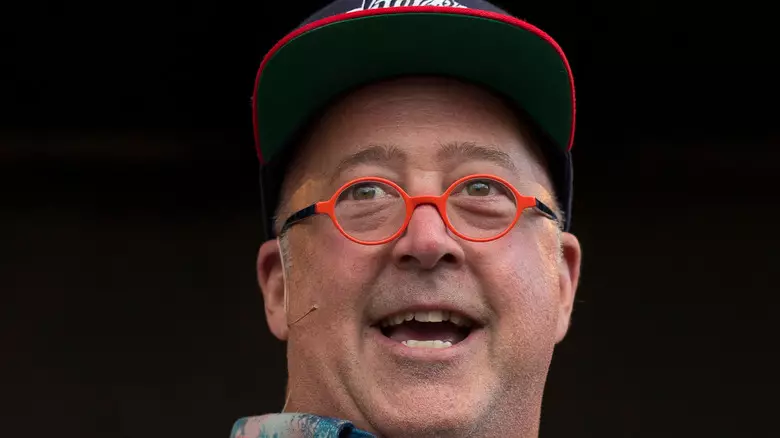 Andrew Zimmern dengan kepala berpaling memakai topi besbol