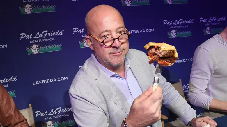 Andrew Zimmern memegang burger yang telah dimakan separa