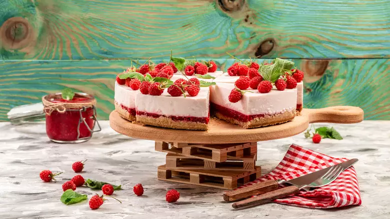 raspberry cheesecake na nakaupo sa isang mesa na may tinidor at kutsilyo