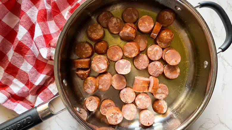 lonchas de salchicha andouille cociñando nunha tixola