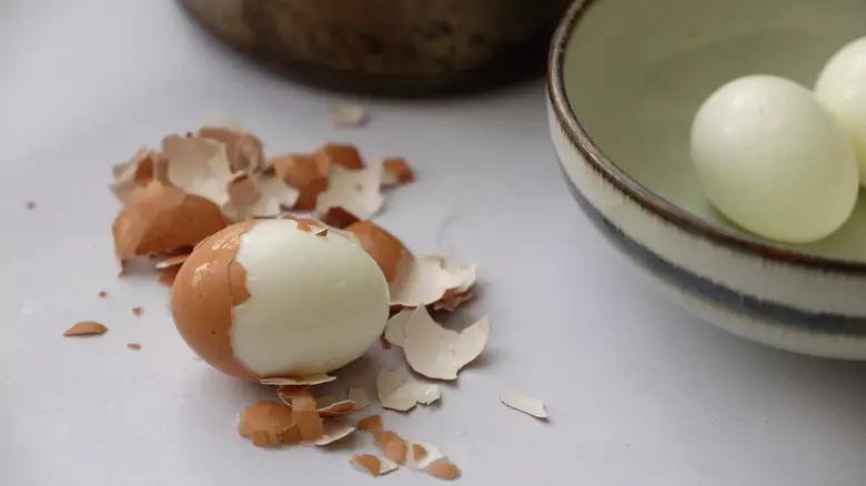 یک تخم مرغ آب پز شکسته روی یک سطح می نشیند