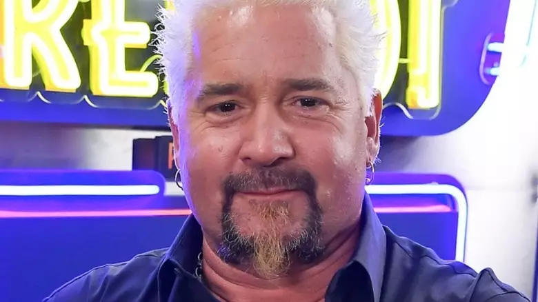 Guy Fieri frente a un letrero de neón