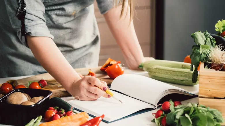 Wanita di dapur membaca buku masak