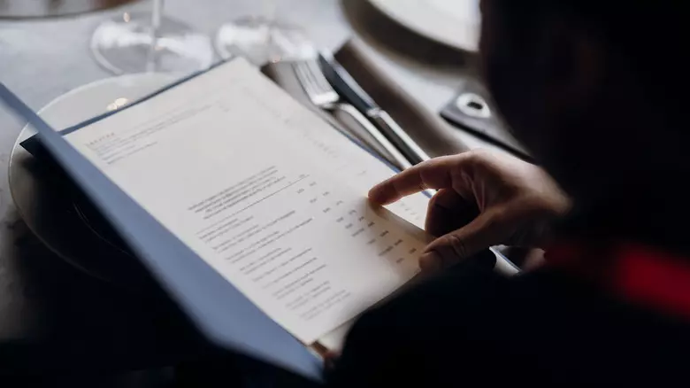 Personne lisant le menu du restaurant à une table