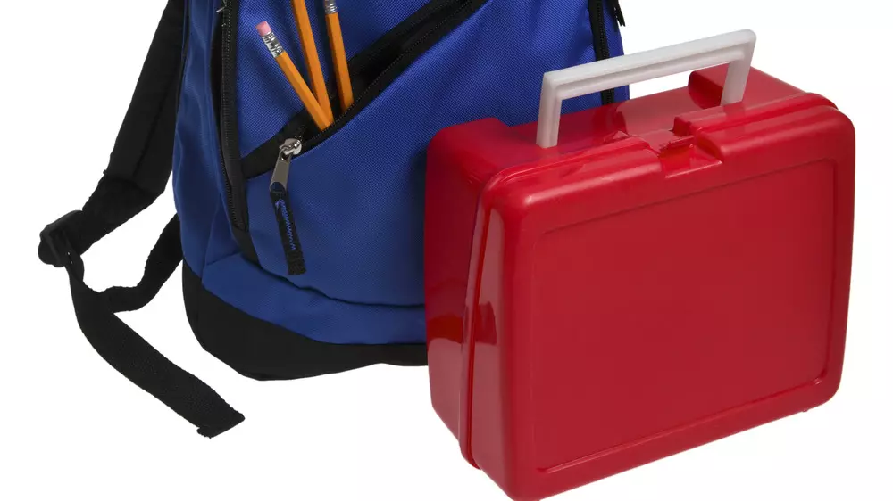 藍色背包前的塑料紅色午餐盒