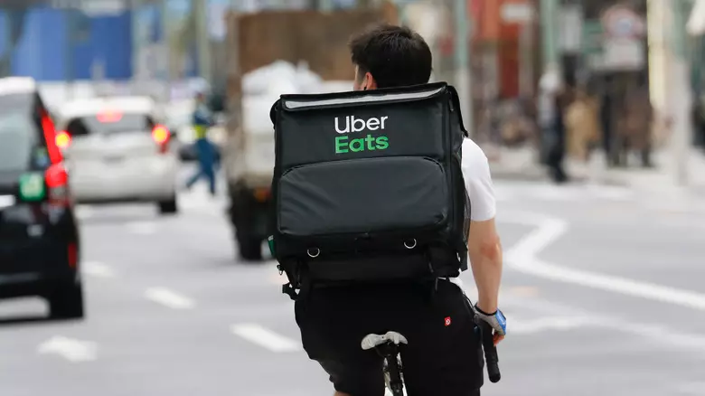 Doručovatel Uber Eats na kole s černou taškou