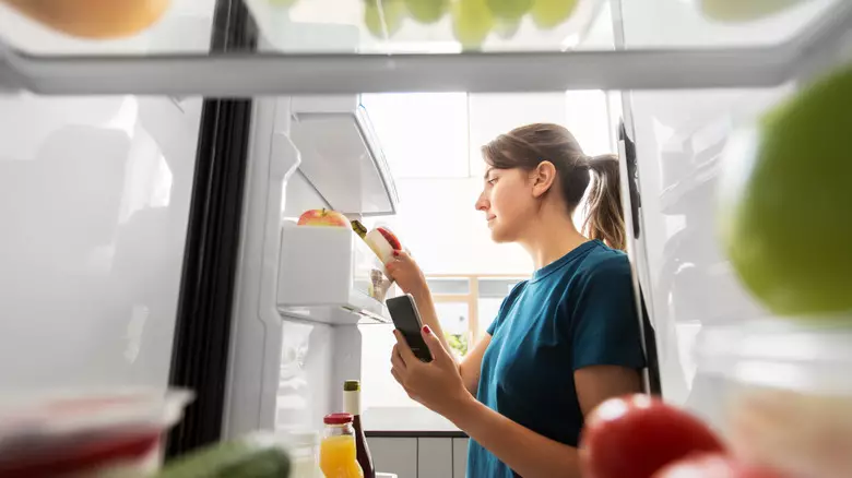 kvinne som sjekker kjøleskapet hennes
