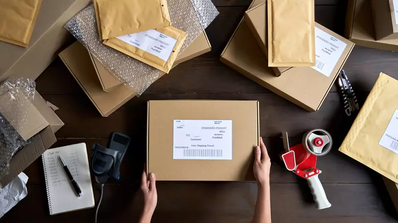 Materijal za pakiranje uključujući mjehurić omot, kartonske kutije i kuverte na stolu.