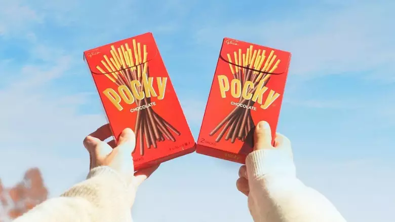 हाथ में चॉकलेट पॉकी के दो बक्से आसमान तक पकड़े हुए हैं