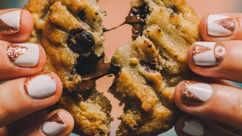 Personne tenant un cookie aux pépites de chocolat gluant