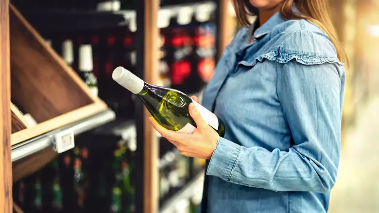 nő vásárol bort a borfolyosón