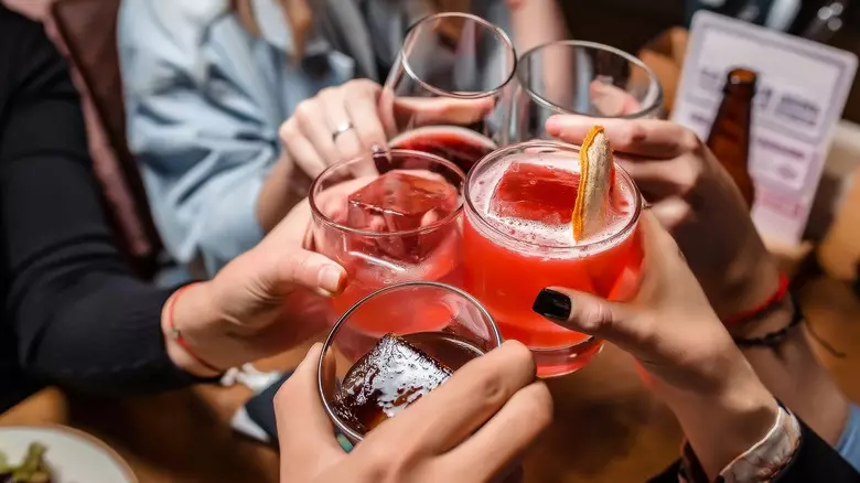 Prieteni prăjind cu cocktail-uri roșii