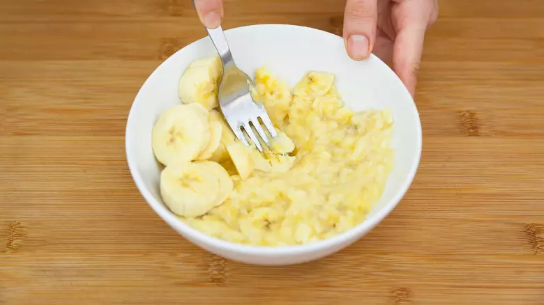 Plátanos triturados con un tenedor en un tazón blanco