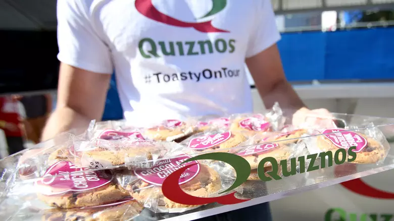 Angajat Quiznos care poartă tava pentru prăjituri