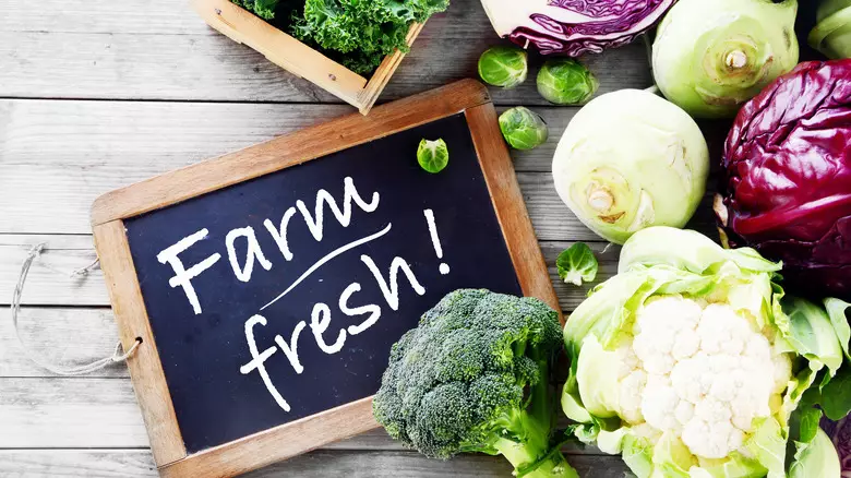 Farm Fresh ဟူသော ဆိုင်းဘုတ်ဘေးတွင် ဟင်းသီးဟင်းရွက်များ အစုံရှိသည်။