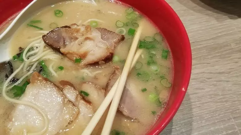 cuenco rojo con caldo cremoso y palillos