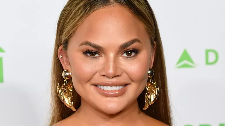 Chrissy Teigen huet orange Kleed un