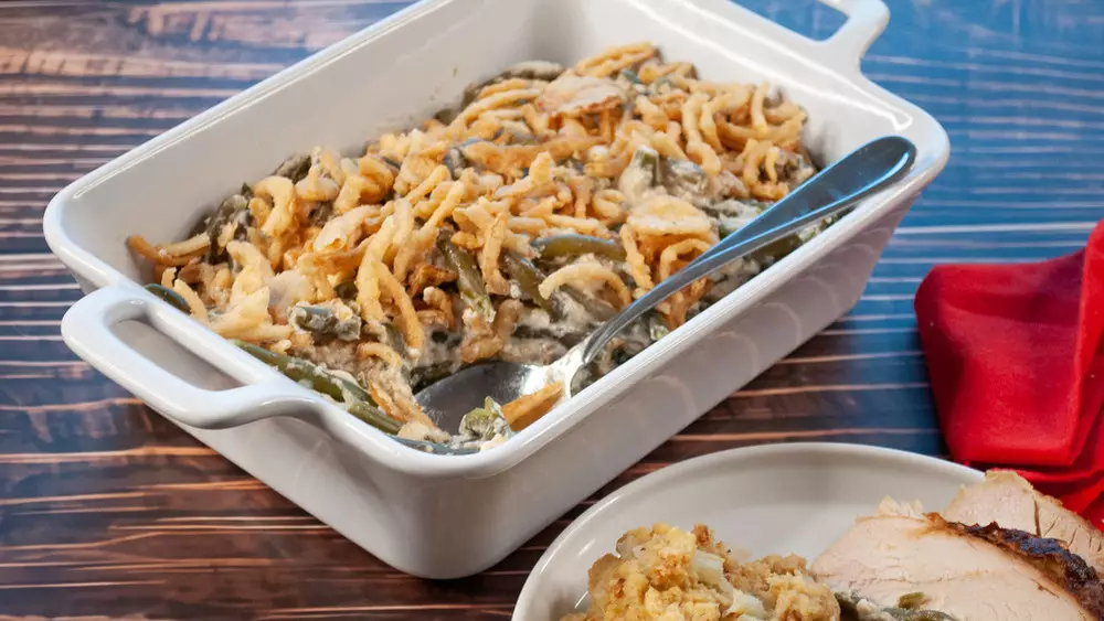 Green bean casserole sa puting baking dish sa ibabaw ng kahoy