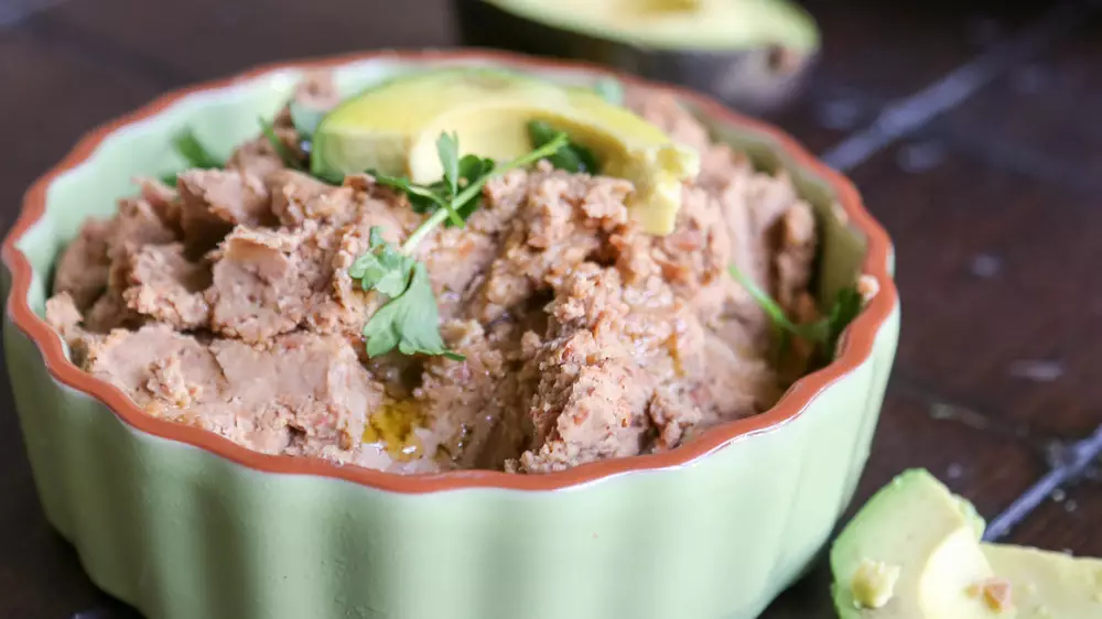 Refried beans sa light green bowl na may cilantro