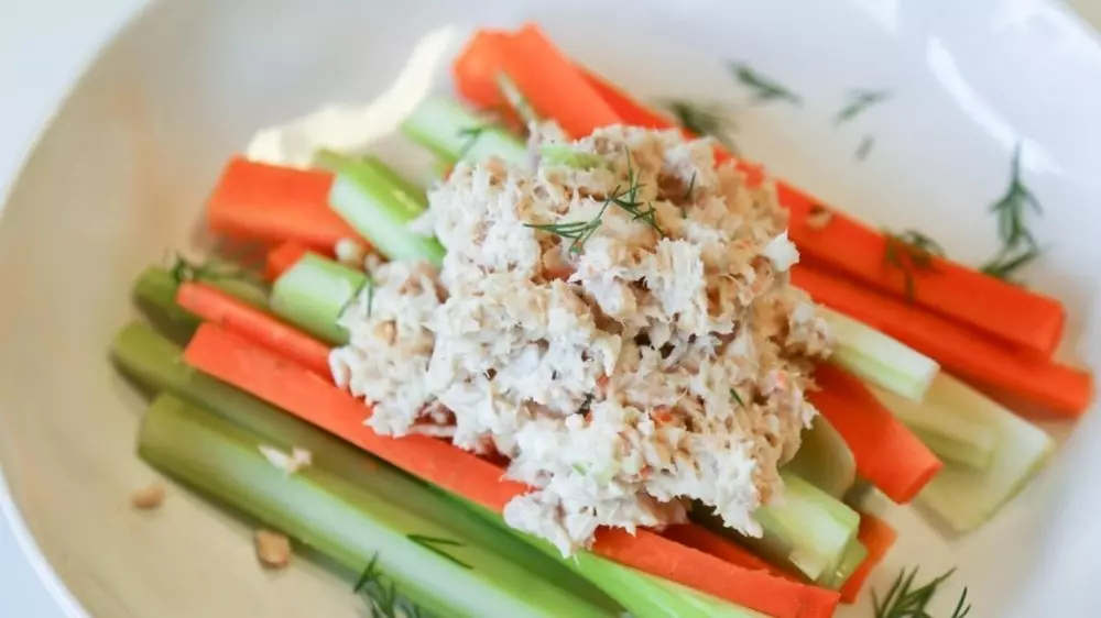 Ensalada de atún con apio, cenorias e endro nun prato branco