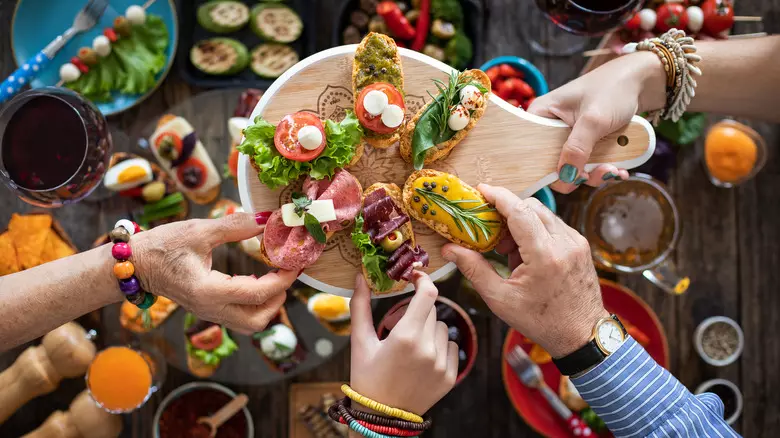 Nekoliko ruku skida tapas sa daske za posluživanje